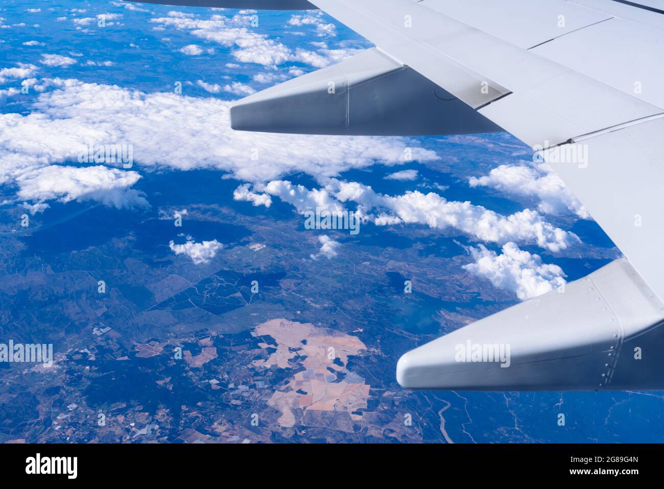 A view from an airplane window with the wing visible above white clouds ...