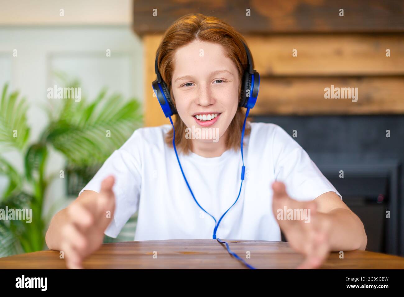 Photo of a smiley red-haired teenager during an online video call. He ...