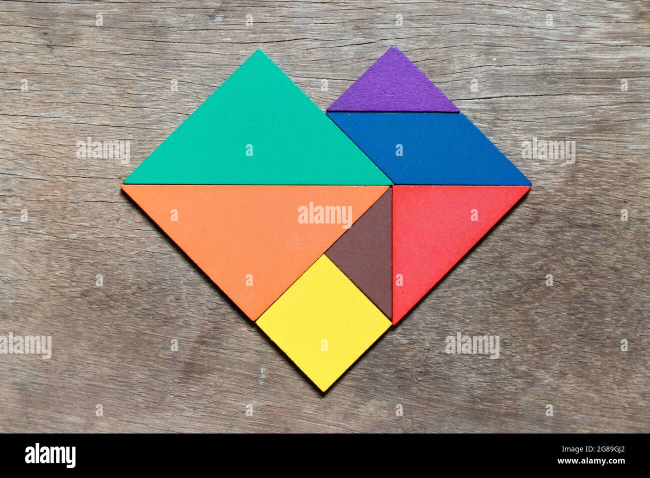 Color tangram puzzle in heart shape on wood background (Concept for ...