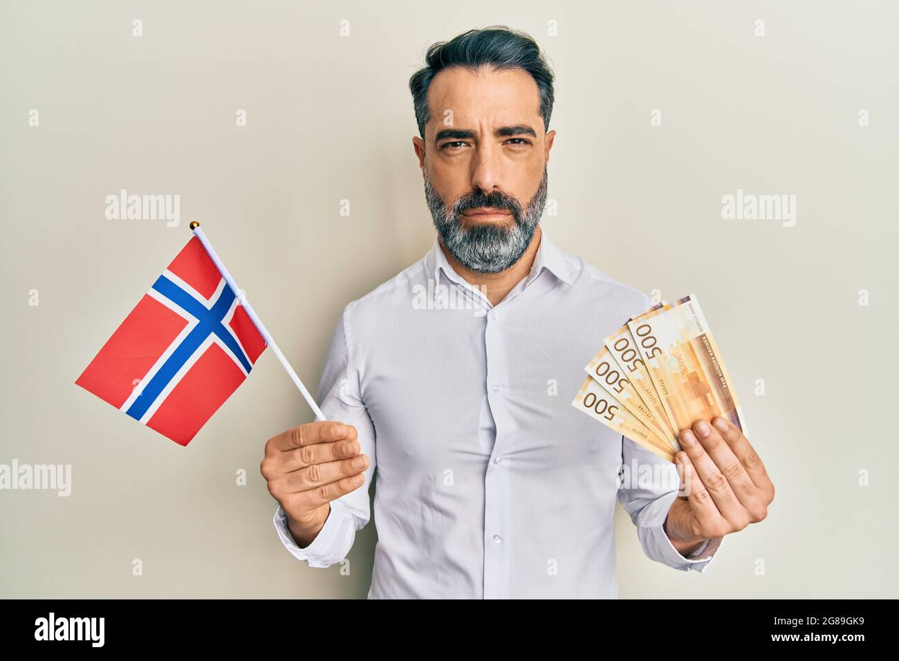 Middle age man with beard and grey hair holding norway flag and krone ...