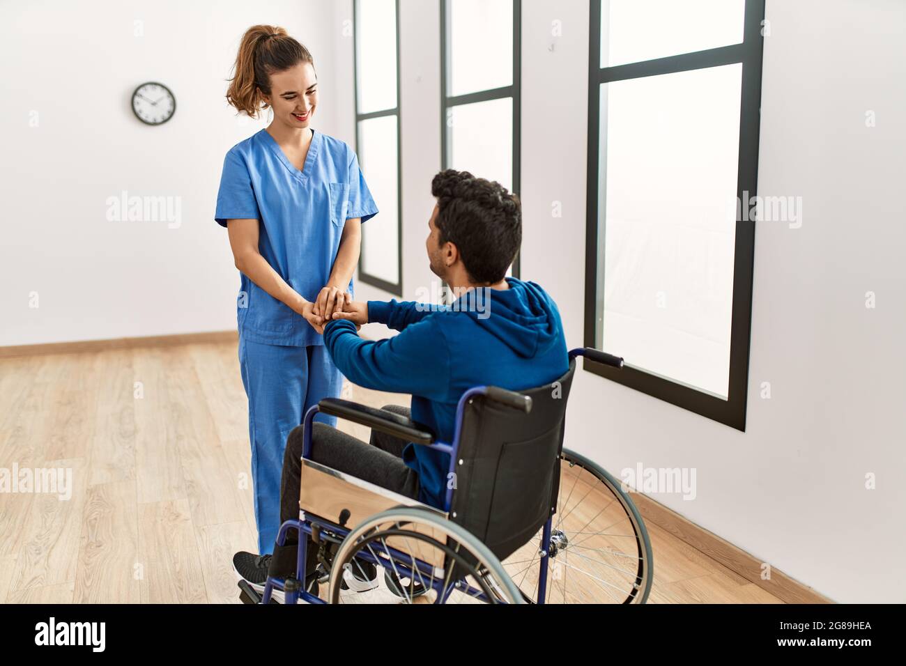 Young disabled man and physiotherapist smiling happy shaking hands at ...