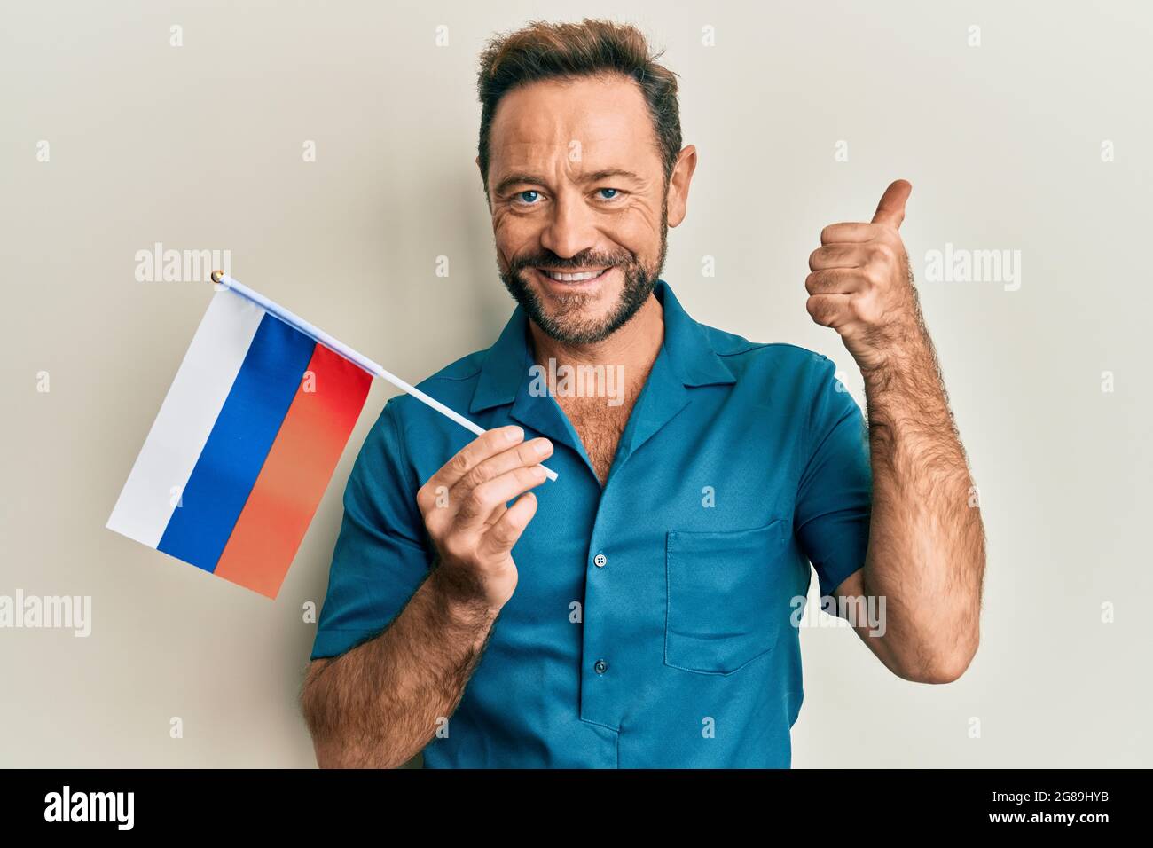 Middle age man holding russia flag smiling happy and positive, thumb up ...