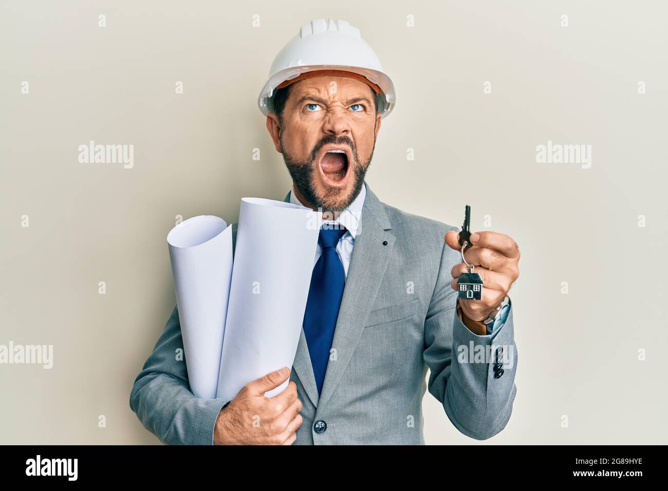 Middle age architect man wearing safety helmet holding blueprints and ...