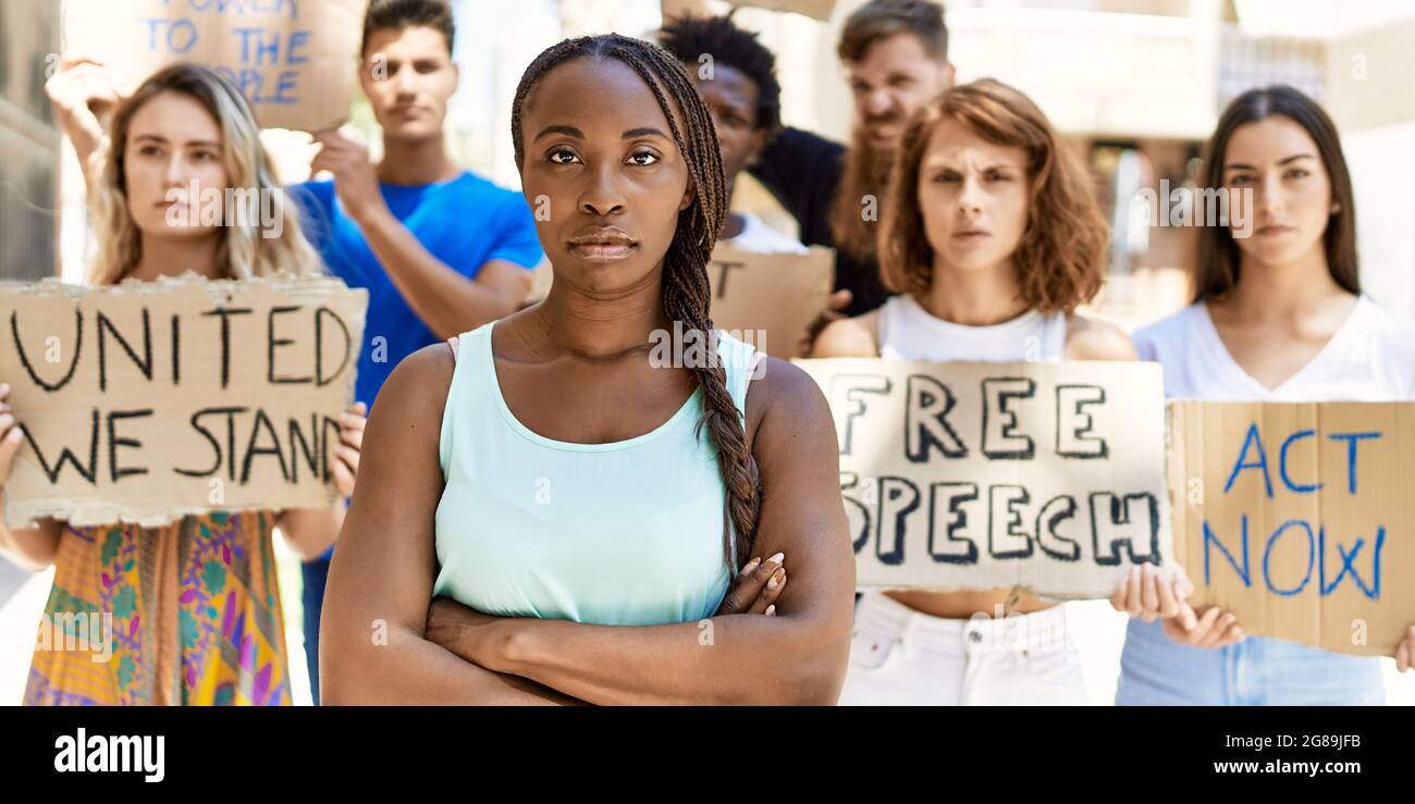 Young activist woman with arms crossed gesture standing with a group of ...