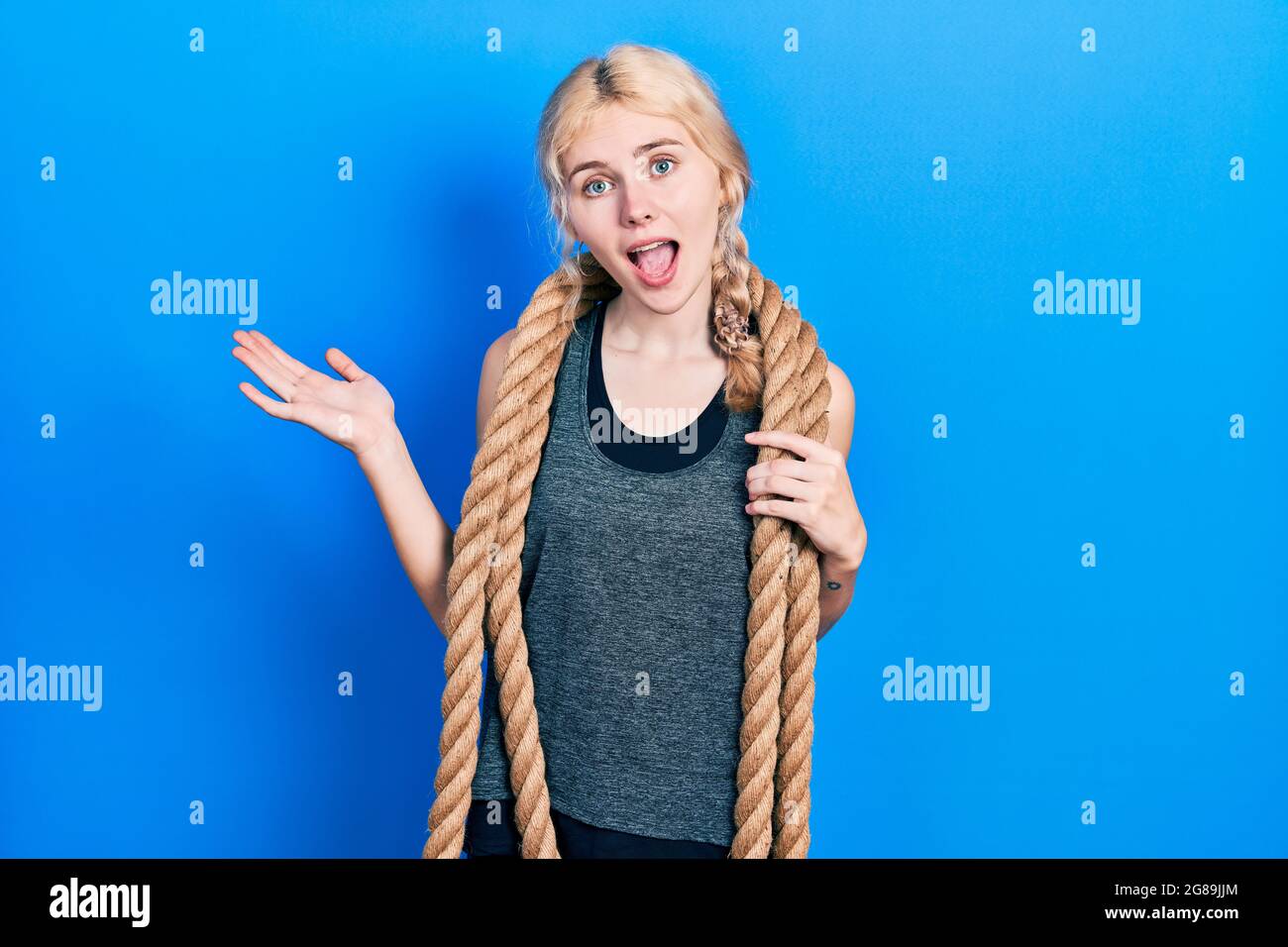 Beautiful caucasian woman with blond hair training with battle rope ...