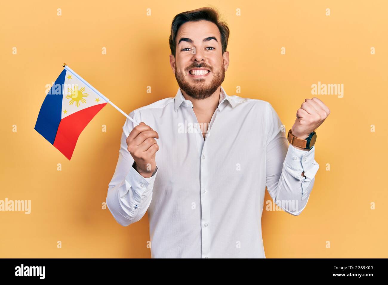 Handsome caucasian man with beard holding philippines flag screaming ...