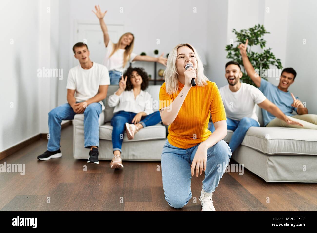Group of young friends having party singing song using microphone at ...