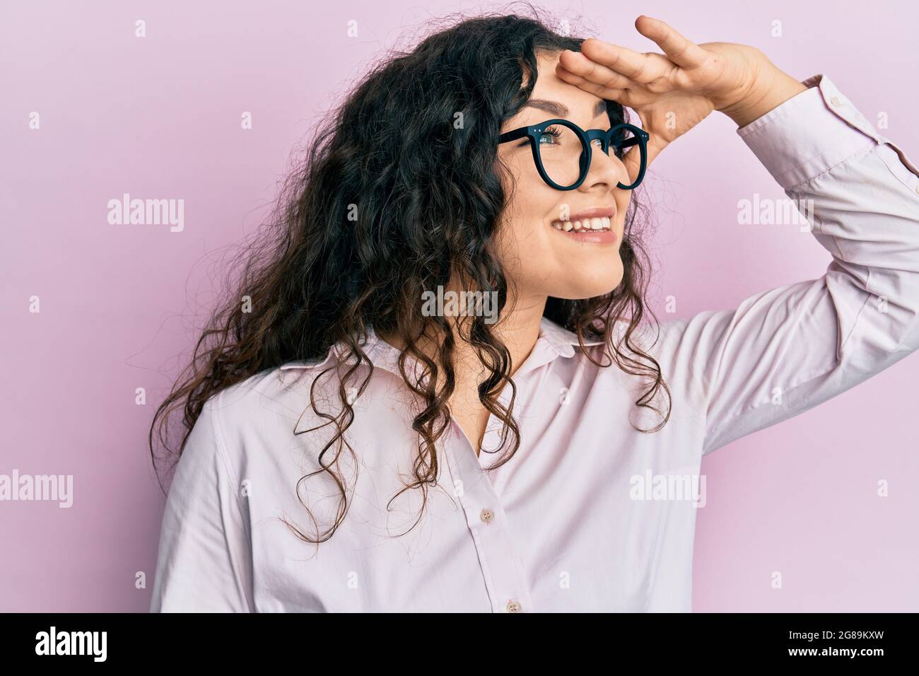 Young brunette woman with curly hair wearing casual clothes and glasses ...