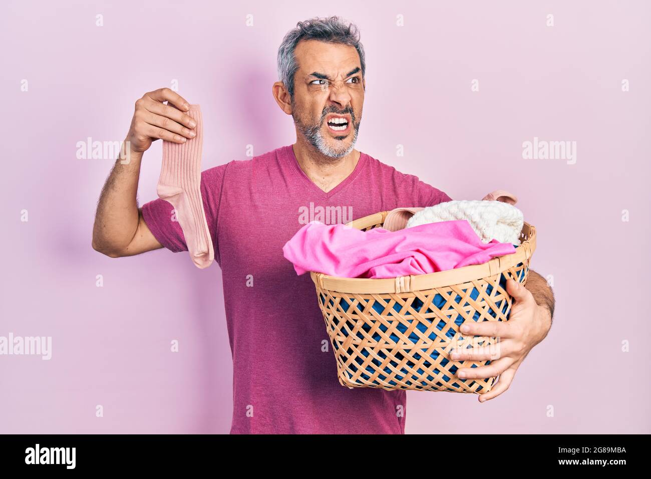Handsome middle age man with grey hair holding laundry basket and dirty ...