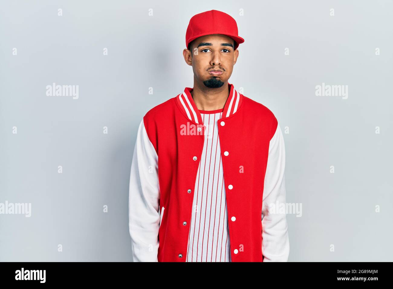 Young african american man wearing baseball uniform puffing cheeks with ...