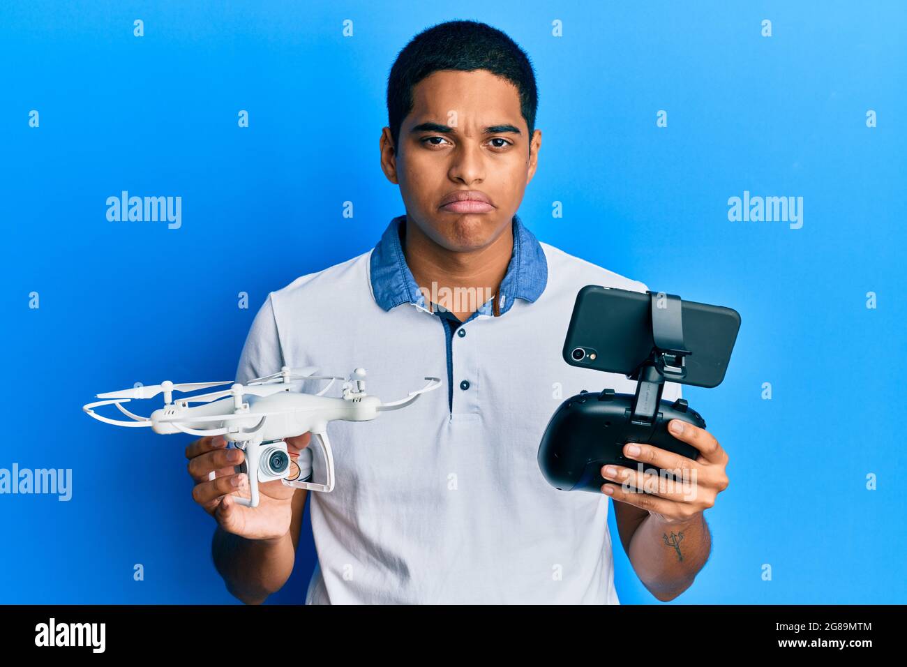Young handsome hispanic man using drone holding remote control ...