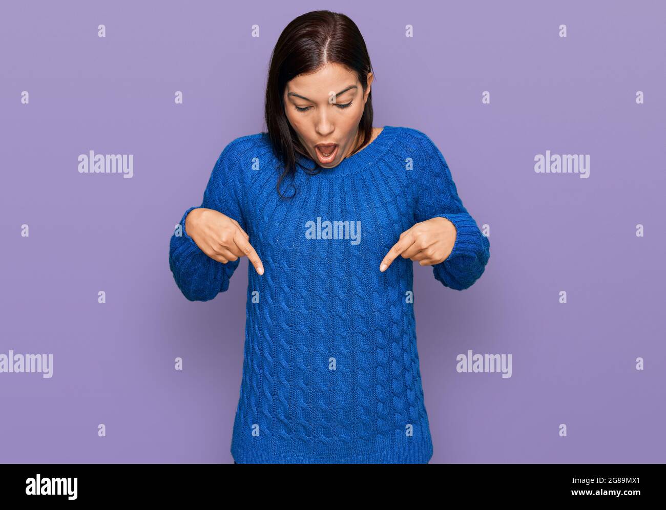 Young hispanic woman wearing casual clothes pointing down with fingers ...