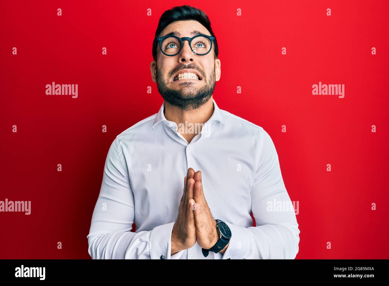 Young hispanic businessman wearing shirt and glasses begging and ...