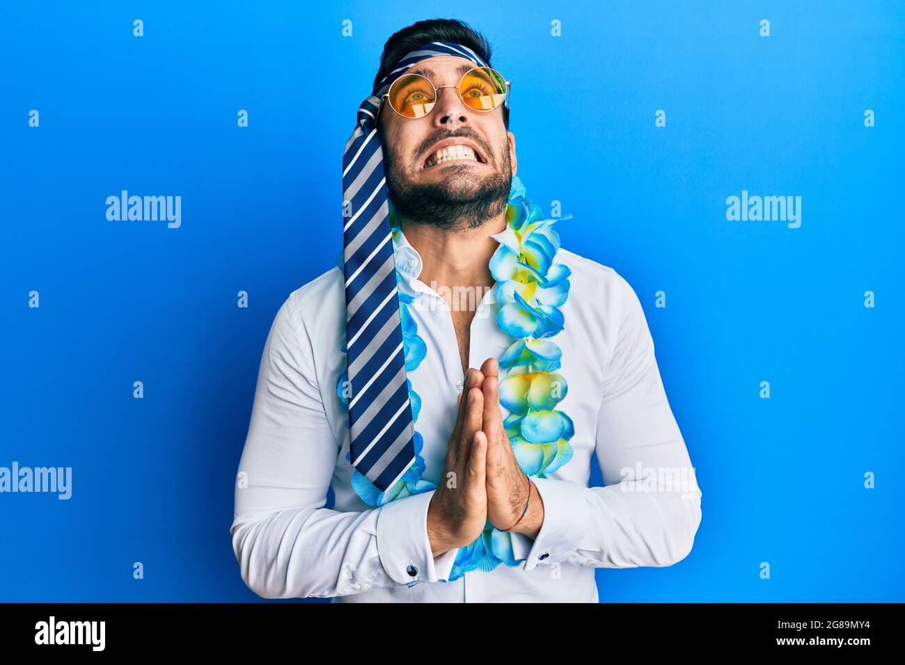 Young hispanic businessman wearing party funny style with tie on head ...