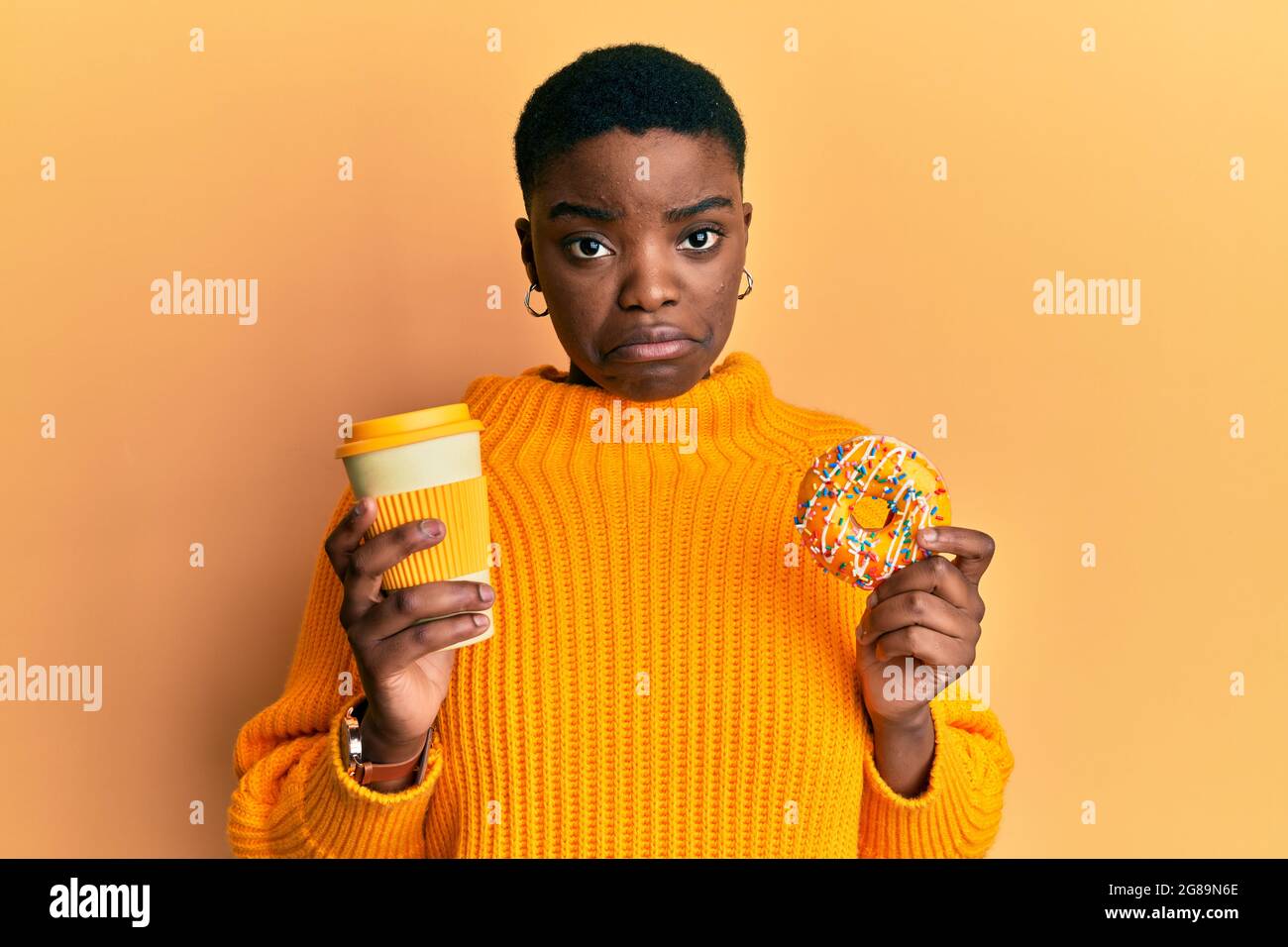 Young african american woman eating doughnut and drinking take away ...