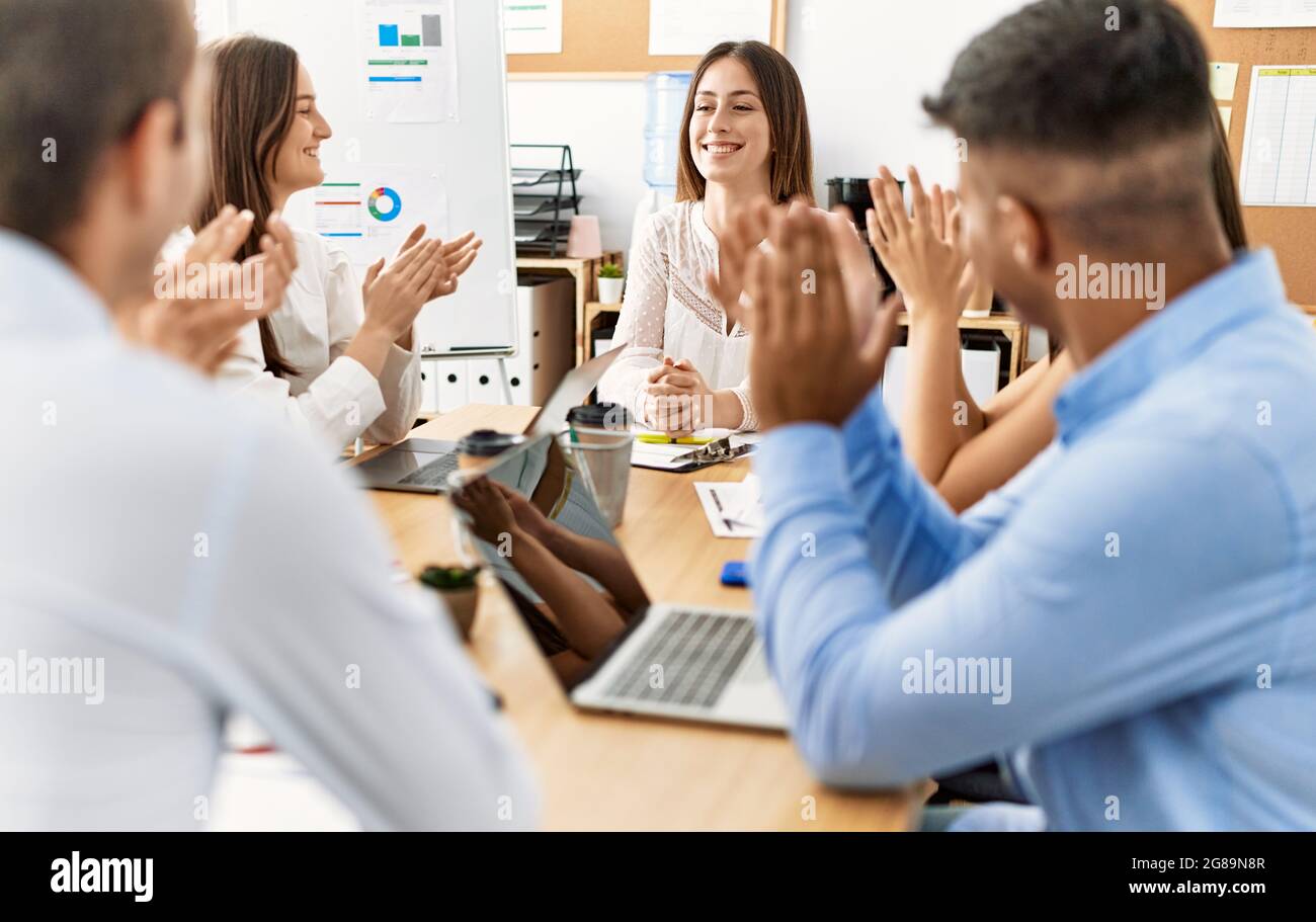 Group of business workers smiling and clapping to partner at the office ...