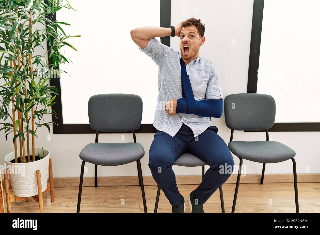Handsome young man sitting at doctor waiting room with arm injury crazy ...