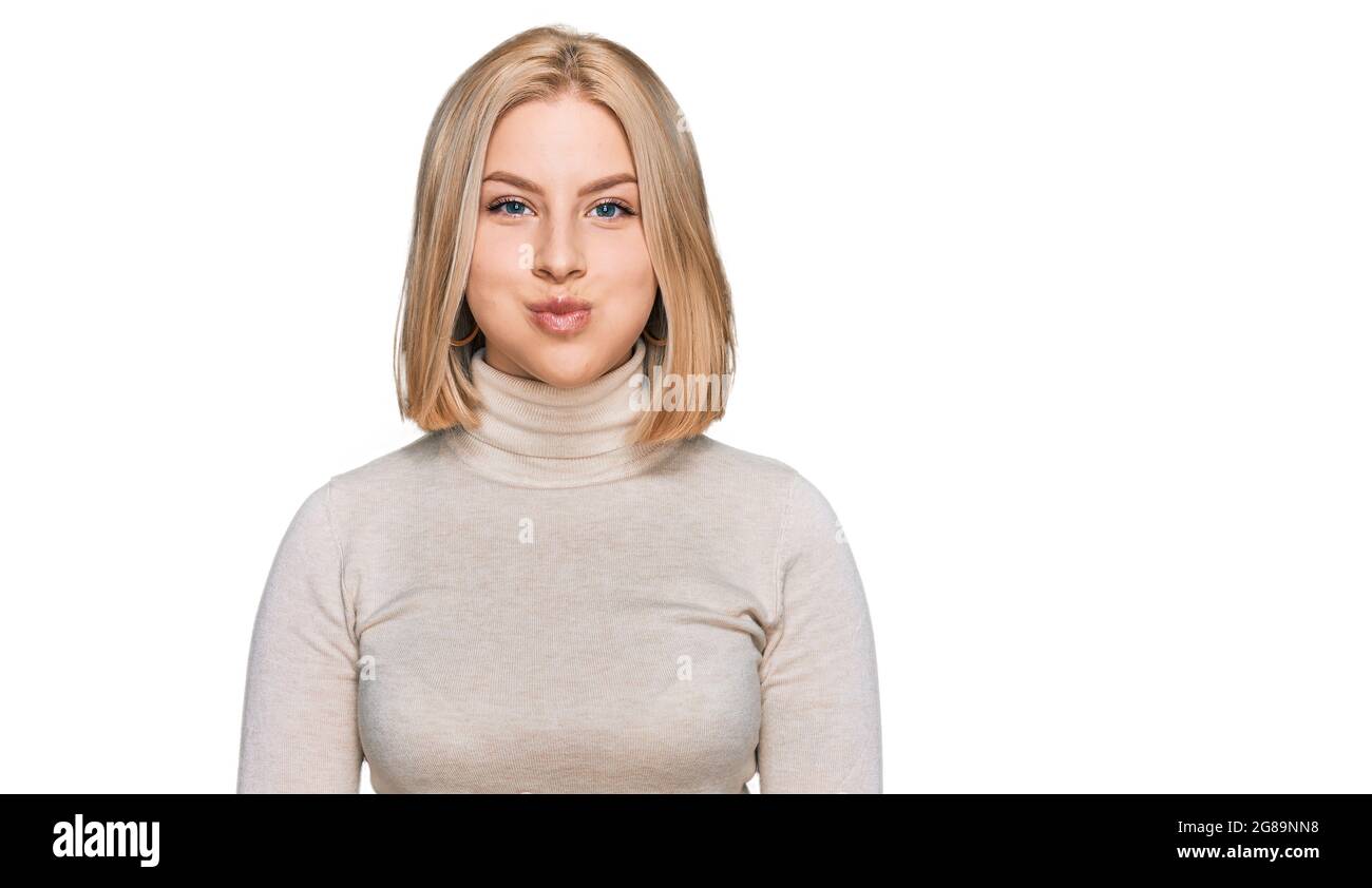 Young blonde woman wearing casual clothes puffing cheeks with funny ...