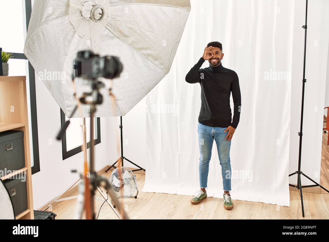 Young hispanic man with beard posing as model at photography studio ...