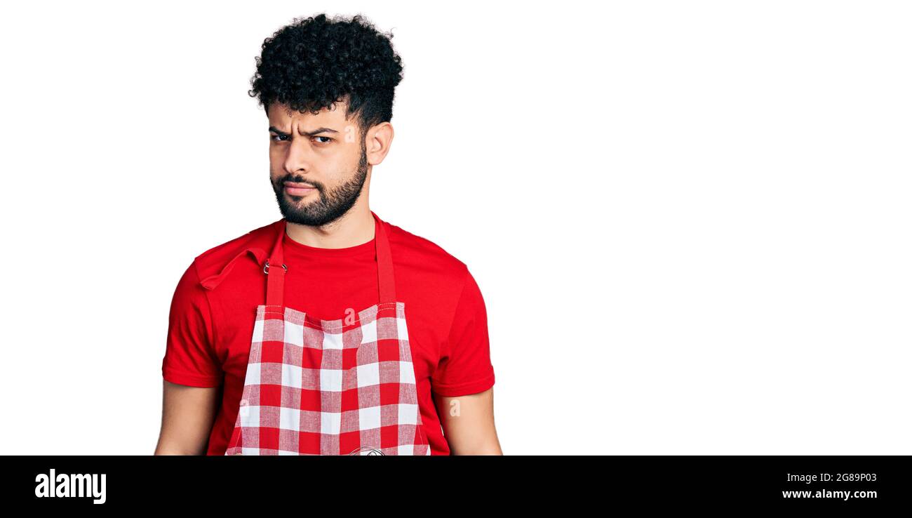 Young arab man with beard wearing cook apron skeptic and nervous ...