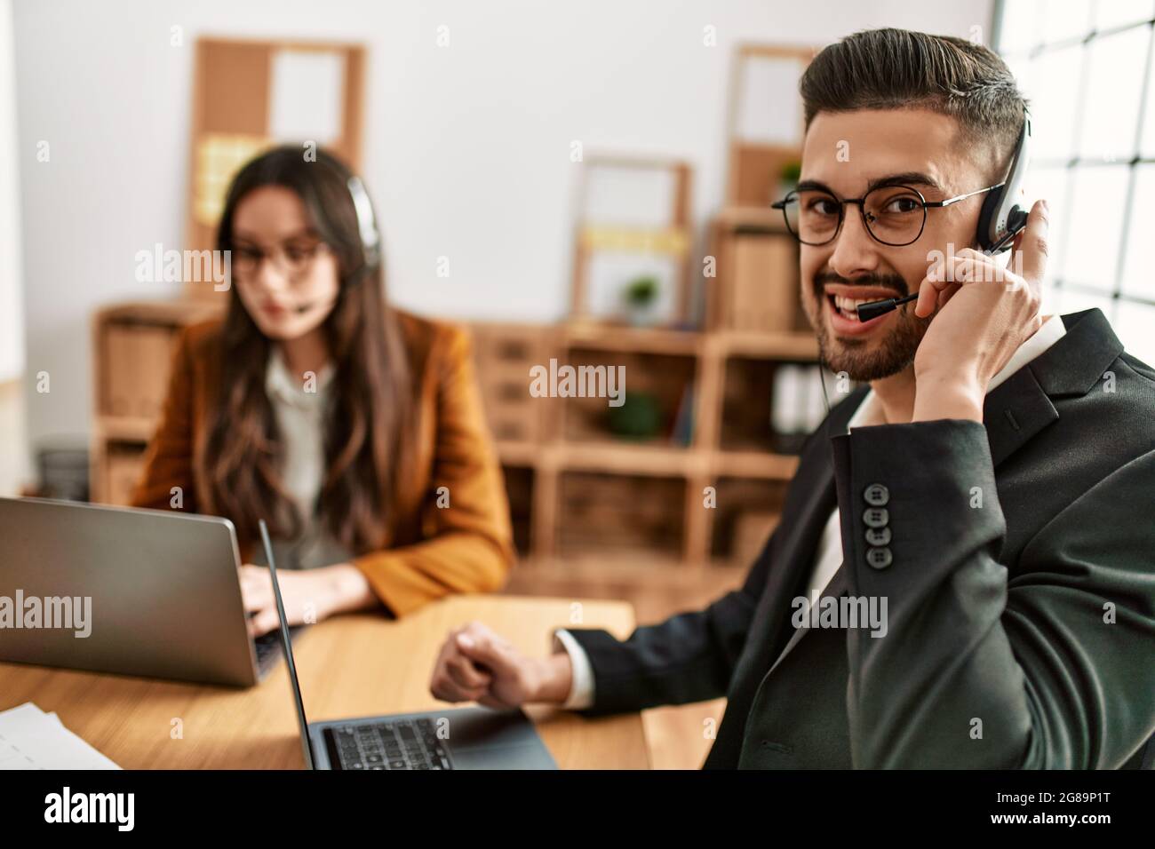 Two hispanic call center agents working at the office Stock Photo - Alamy