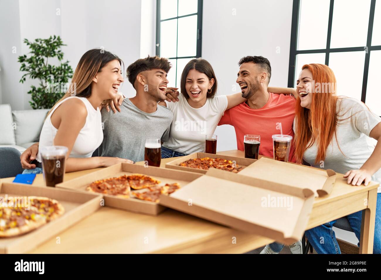 Group of young people smiling happy and hugging eating italian pizza at ...