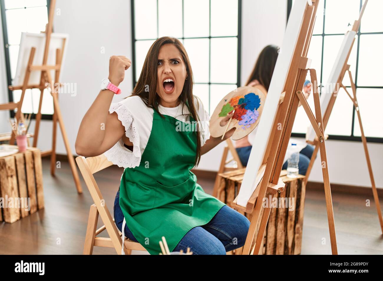 Young hispanic artist women painting on canvas at art studio angry and ...
