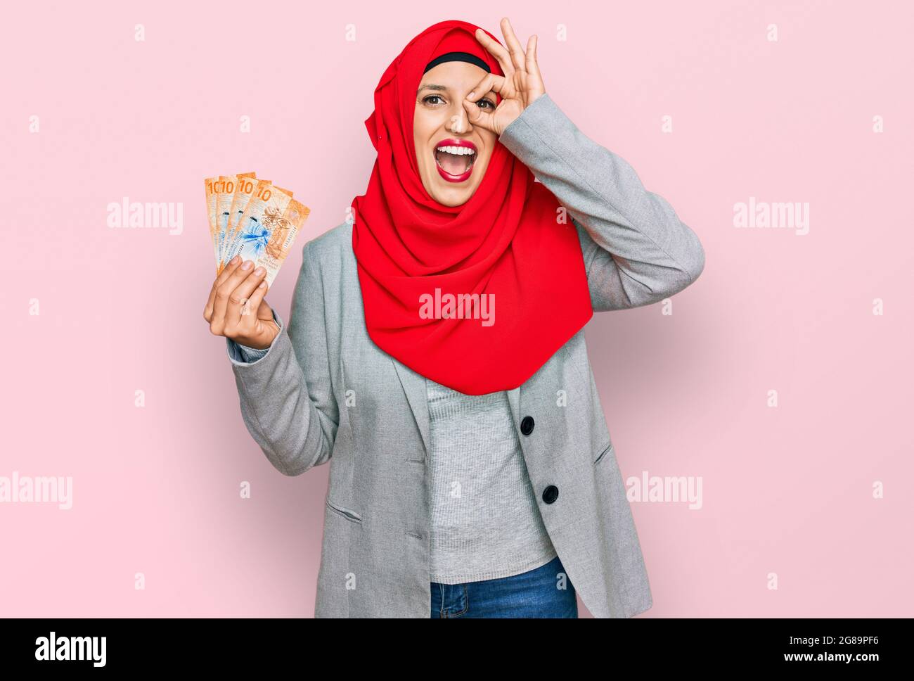 Beautiful hispanic woman wearing islamic hijab holding 10 swiss franc ...