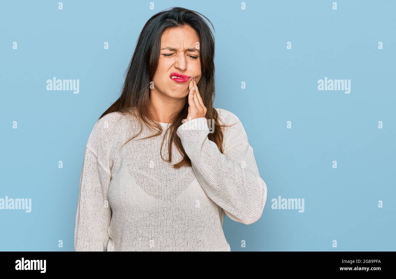 Beautiful hispanic woman wearing casual sweater touching mouth with ...