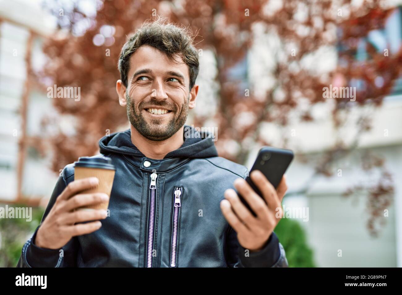 Handsome hispanic man with beard smiling happy outdoors using ...