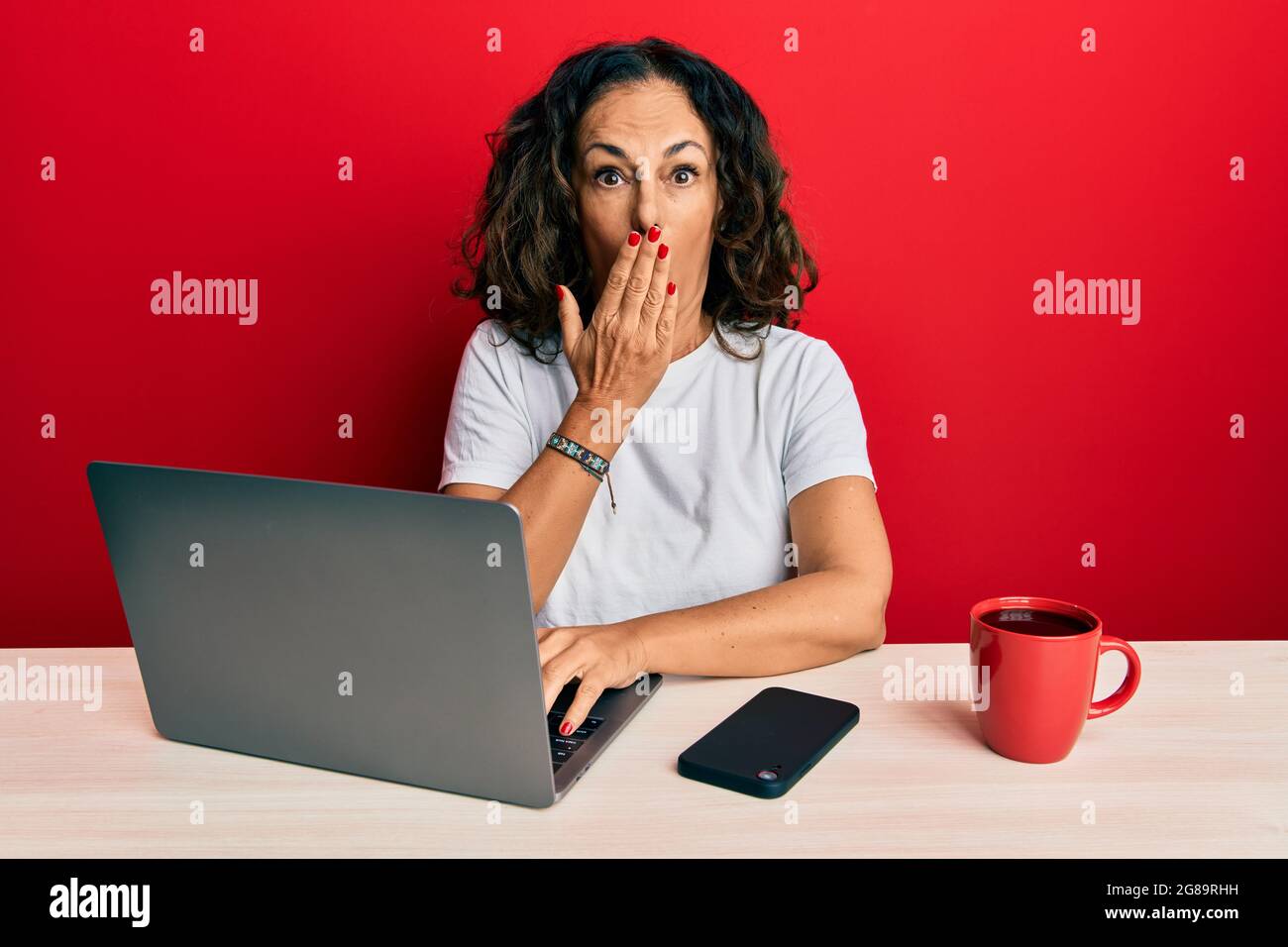 Beautiful middle age woman working at the office using computer laptop ...