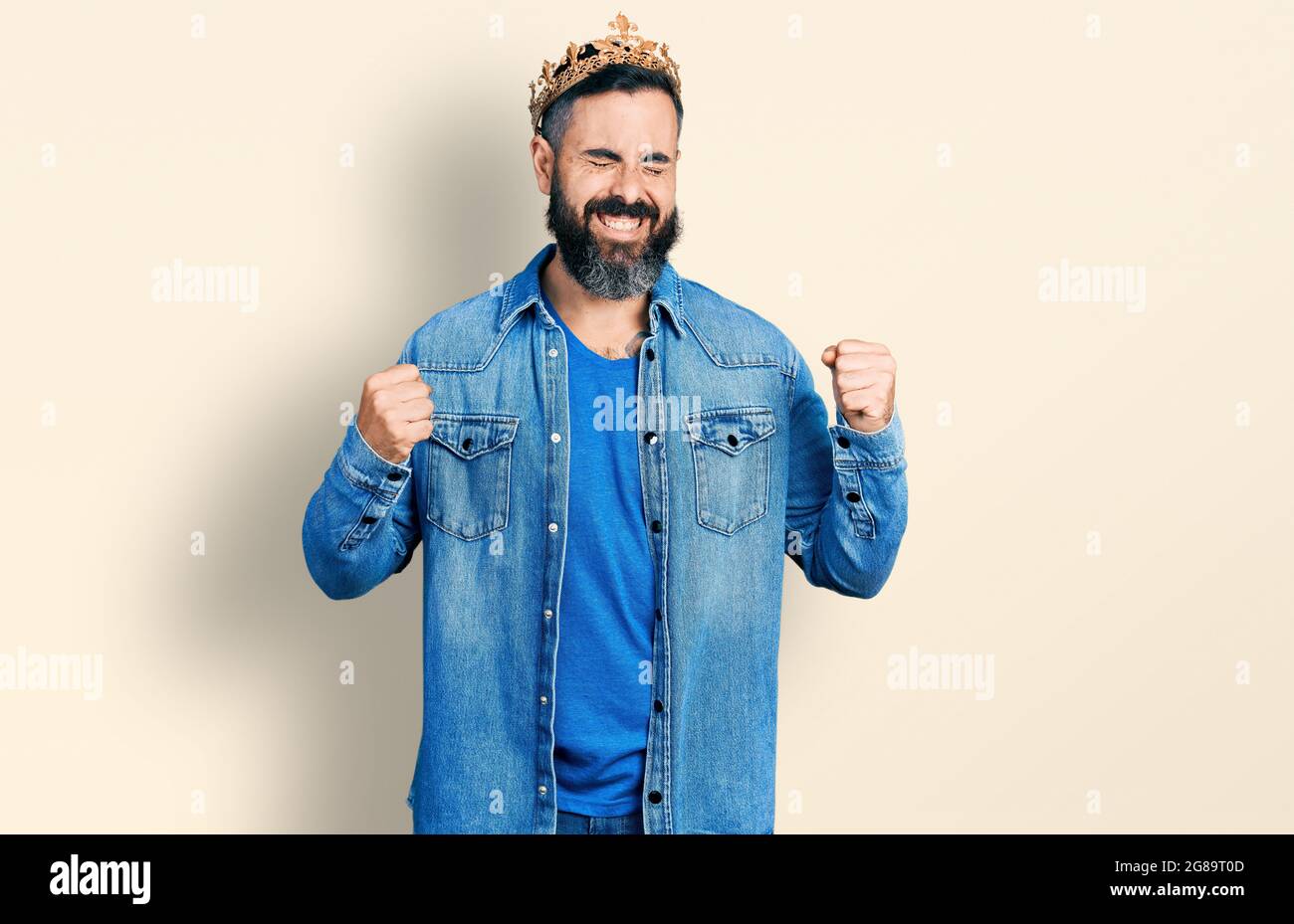 Hispanic man with beard wearing king crown very happy and excited doing ...