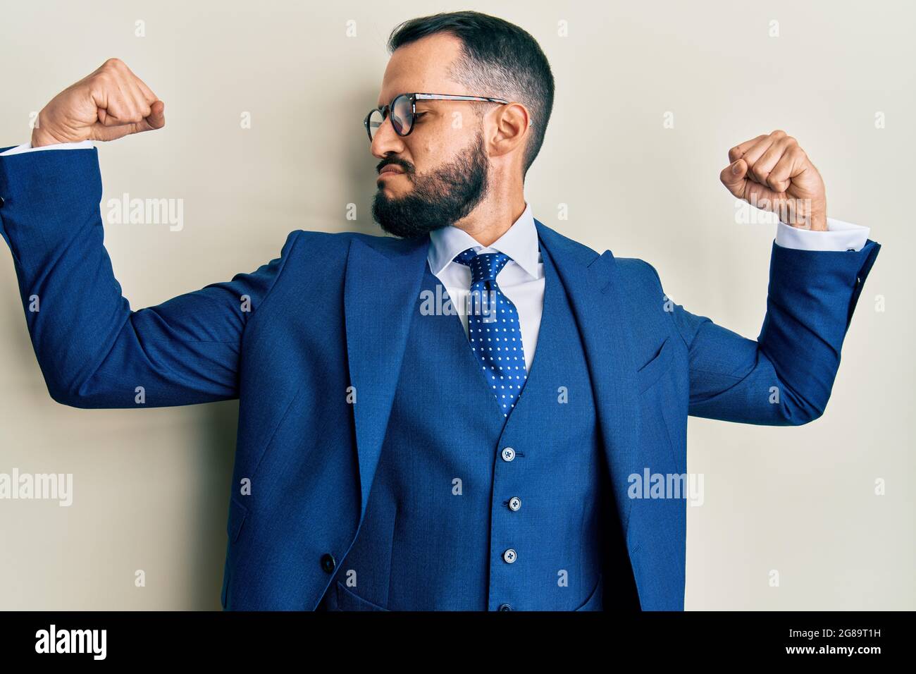 Young man with beard wearing business suit and tie showing arms muscles ...