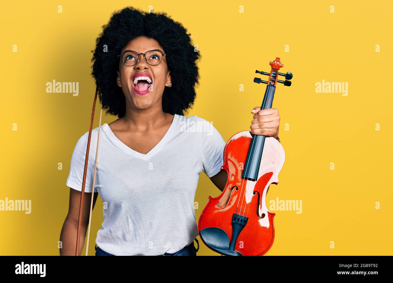 Young african american woman playing violin angry and mad screaming ...