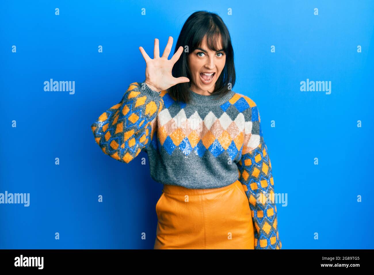 Young hispanic woman wearing casual winter sweater showing and pointing ...