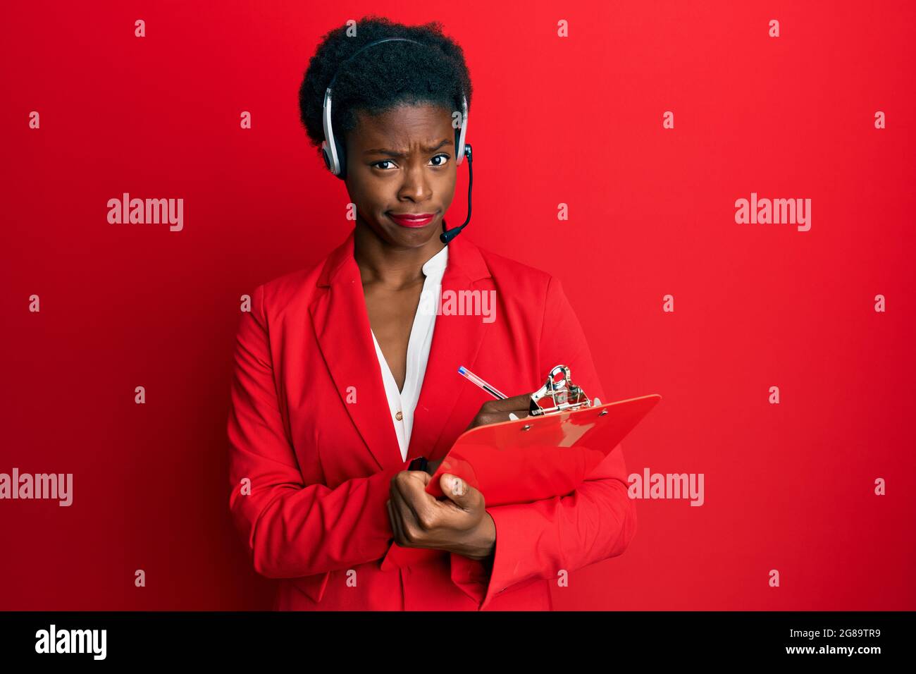 Young african american girl wearing call center agent headset writing ...