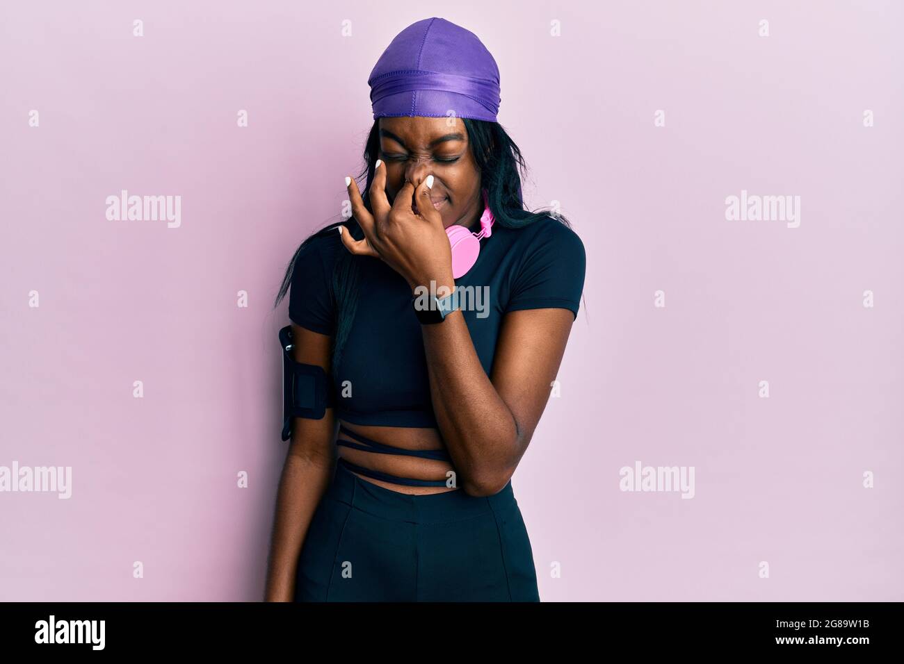 Young african american woman wearing gym clothes and using headphones ...