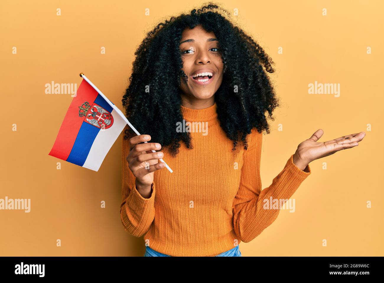 African american woman with afro hair holding serbia flag celebrating ...