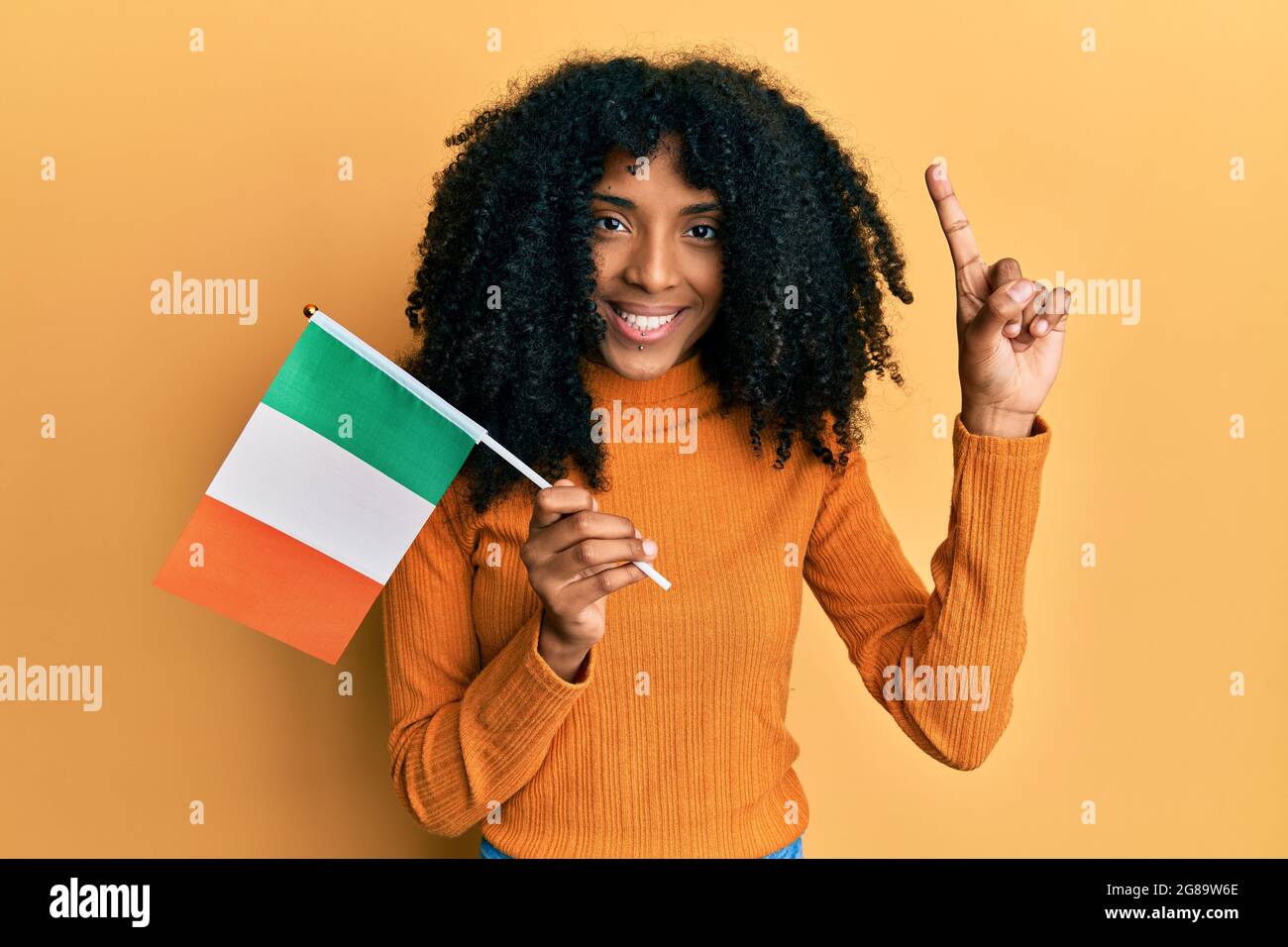 African american woman with afro hair holding ireland flag smiling with ...
