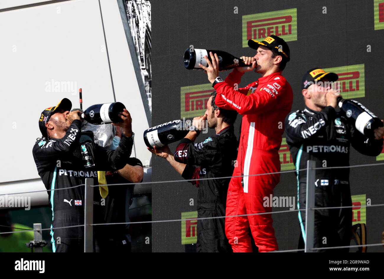 Mercedes' Lewis Hamilton (left) drinks a bottle of champagne as he ...