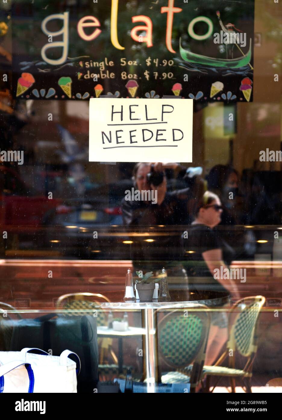 A Help Wanted sign taped to the windwo of a ice cream and gelato parlor ...