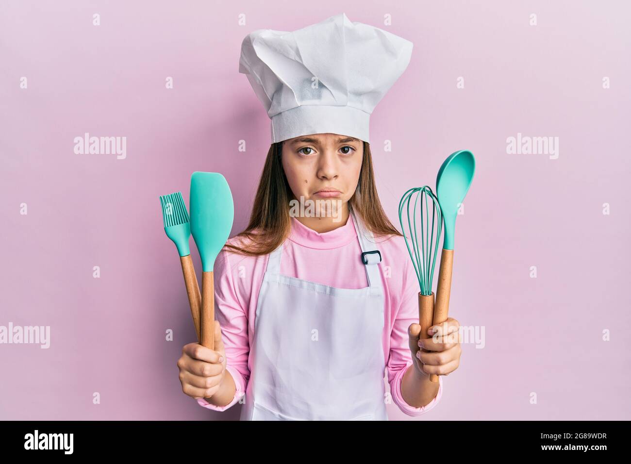 Beautiful brunette little girl wearing professional cook apron holding ...