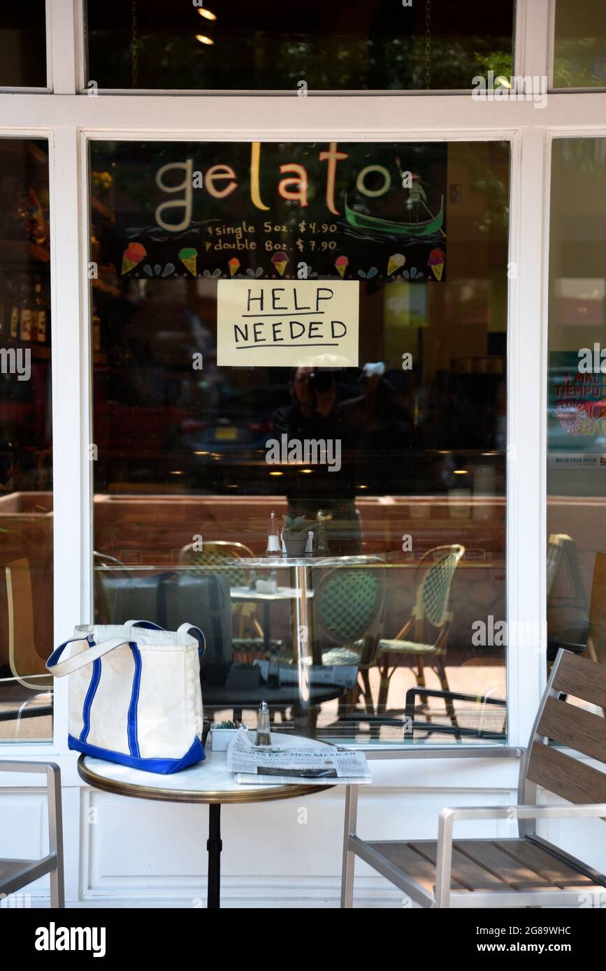 A Help Wanted sign taped to the windwo of a ice cream and gelato parlor ...