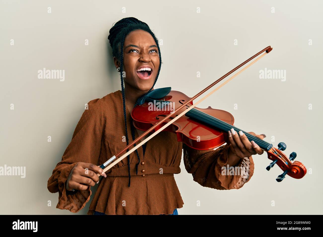 African american woman with braided hair playing violin angry and mad ...