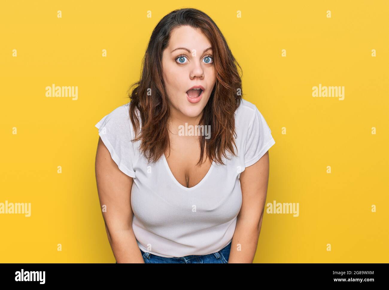 Young plus size woman wearing casual white t shirt afraid and shocked ...