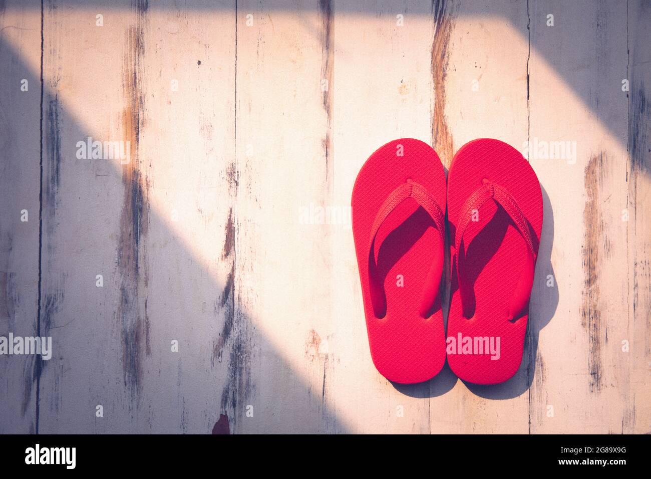 A pair of colorful red rubber slippers popular use on a sand beach and ...