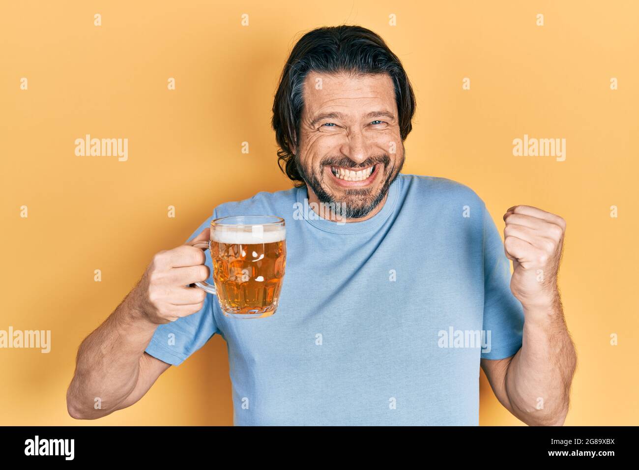 Middle age caucasian man drinking a jar of beer screaming proud ...