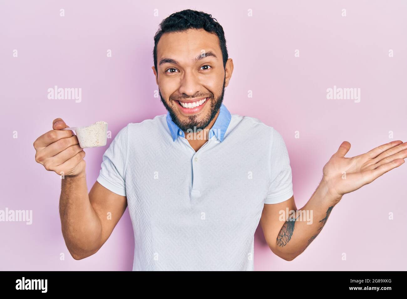 Hispanic man with beard holding white protein powder celebrating ...