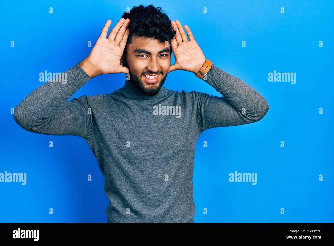 Arab man with beard wearing turtleneck sweater smiling cheerful playing ...