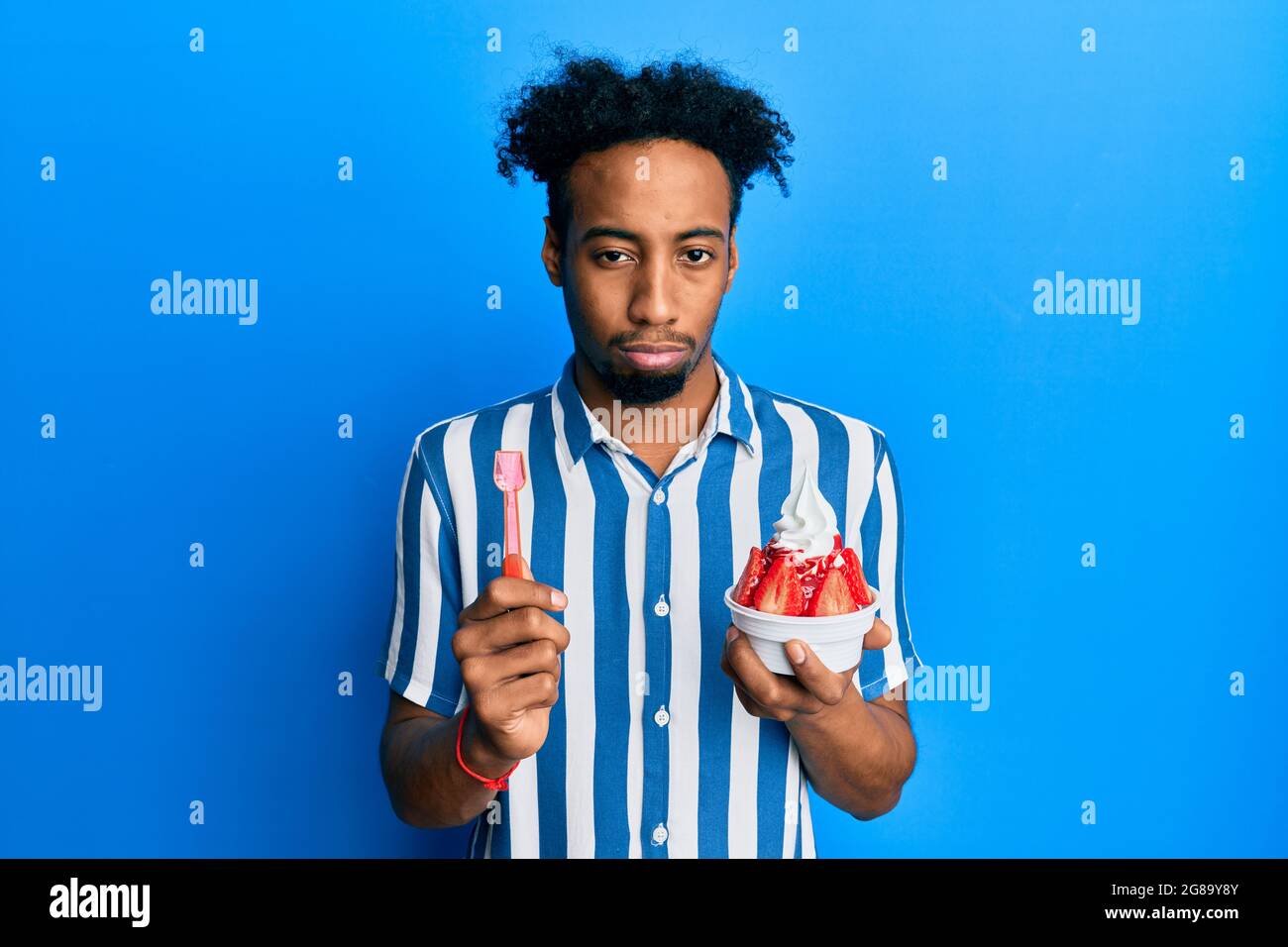 Young african american man with beard eating strawberry ice cream ...